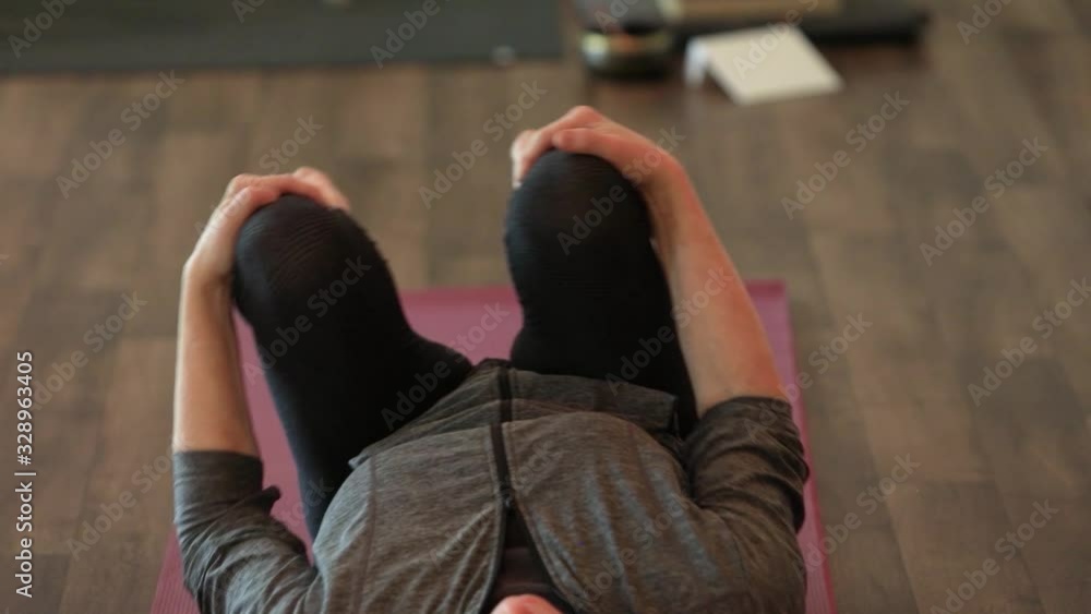 Shallow focus of woman lying on yoga mat practicing knee exercise by ...