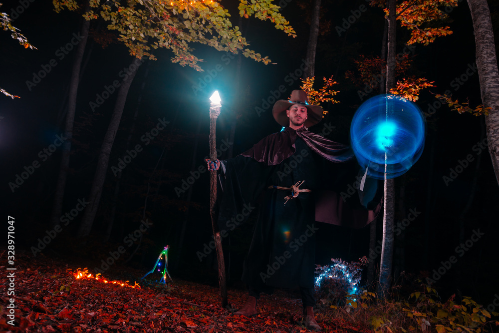 Sorcerer (magician) casting a spell while standing in the magical woods ...