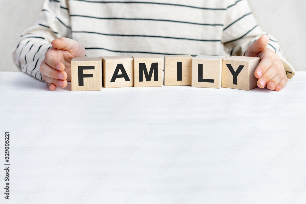Childs hands hold cubes with the alphabet made the word family on the ...