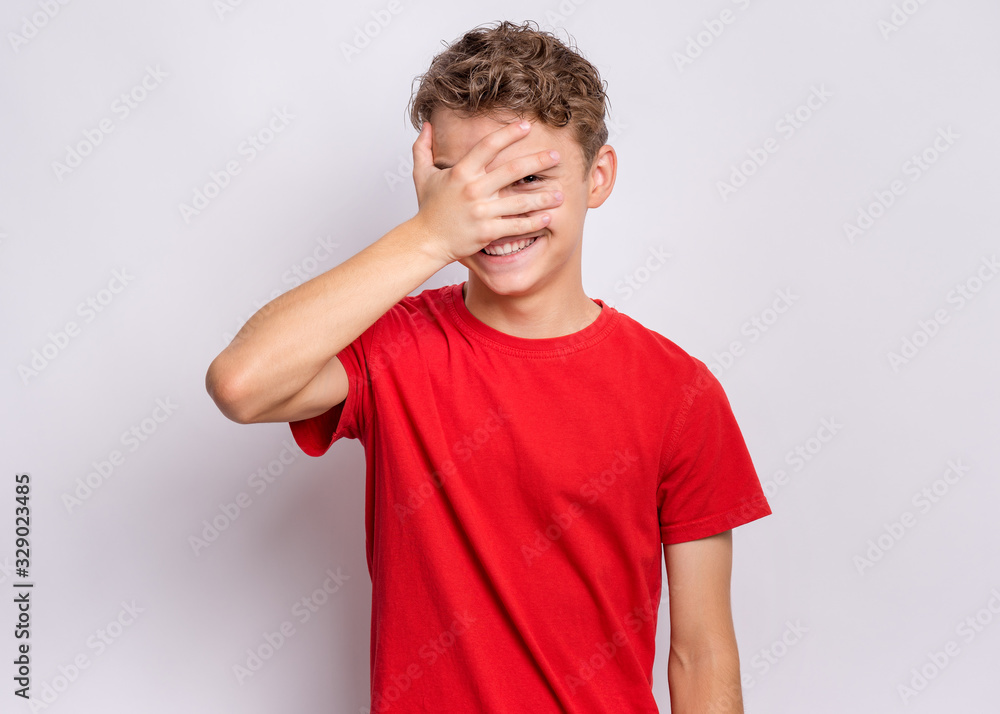 Portrait of happy teen boy looking at camera through his fingers, on ...