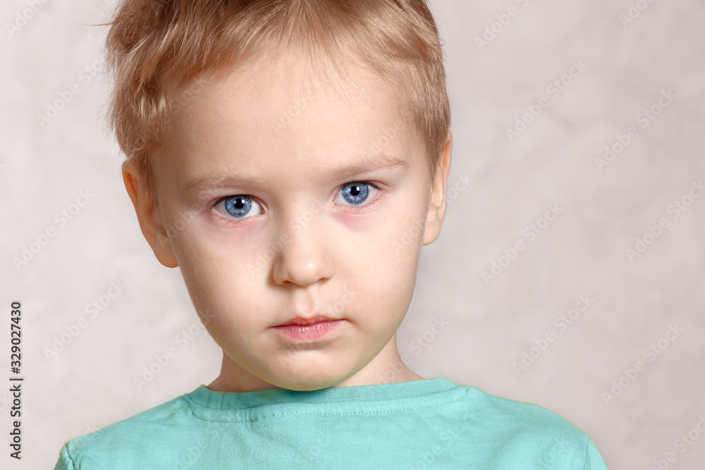 Beautiful and serious caucasian little boy looks right to the camera ...