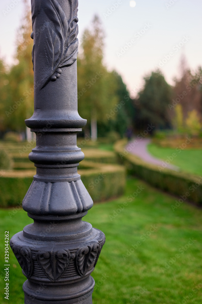 Decorative lamp post column in a park. Ornamental black metal close up ...
