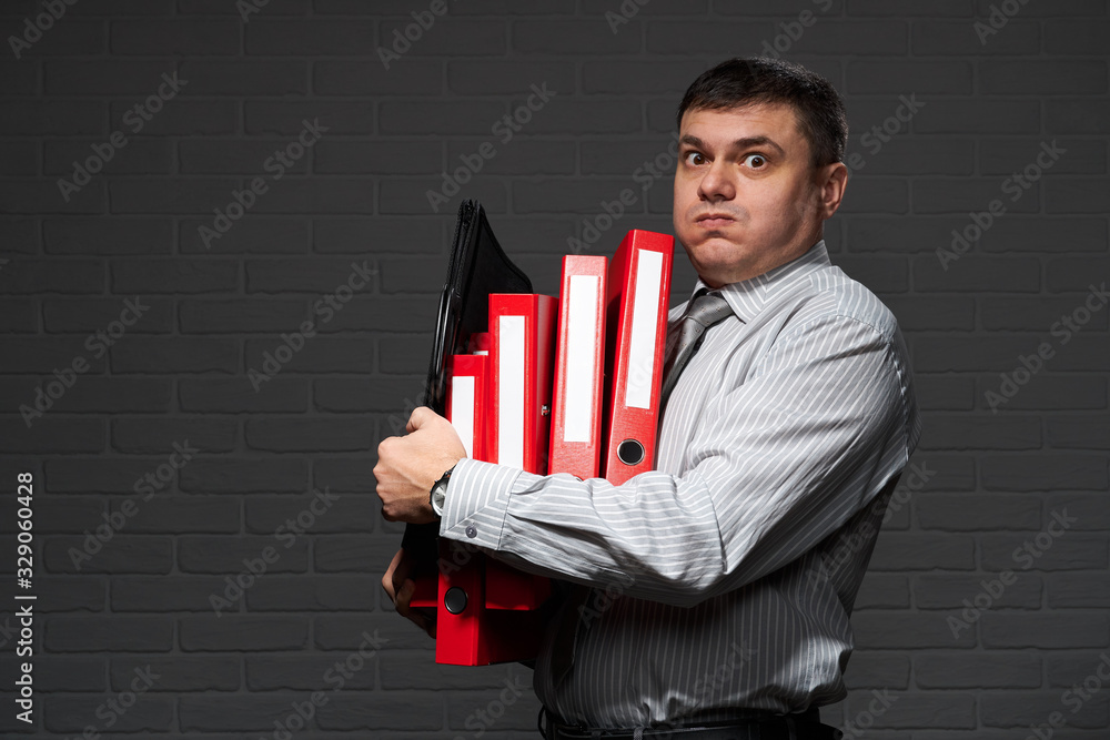 Very busy businessman closeup portrait, posing with red folders ...