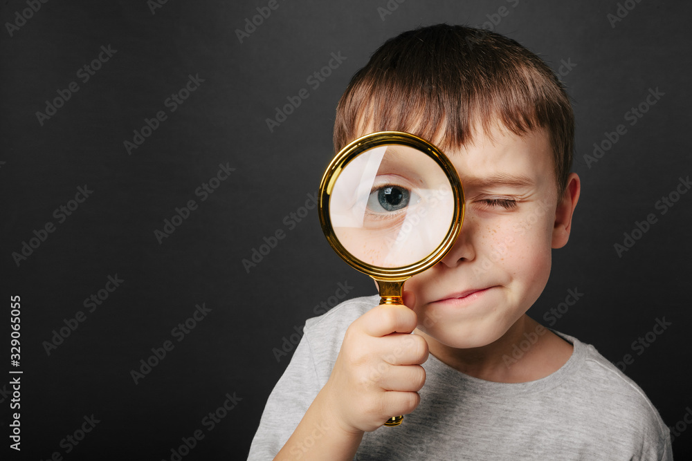 Child see through magnifying glass on the black backgrounds. Big kid ...