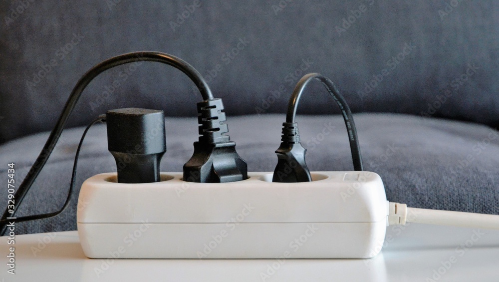 Three different electrical plugs connected to a power strip or ...
