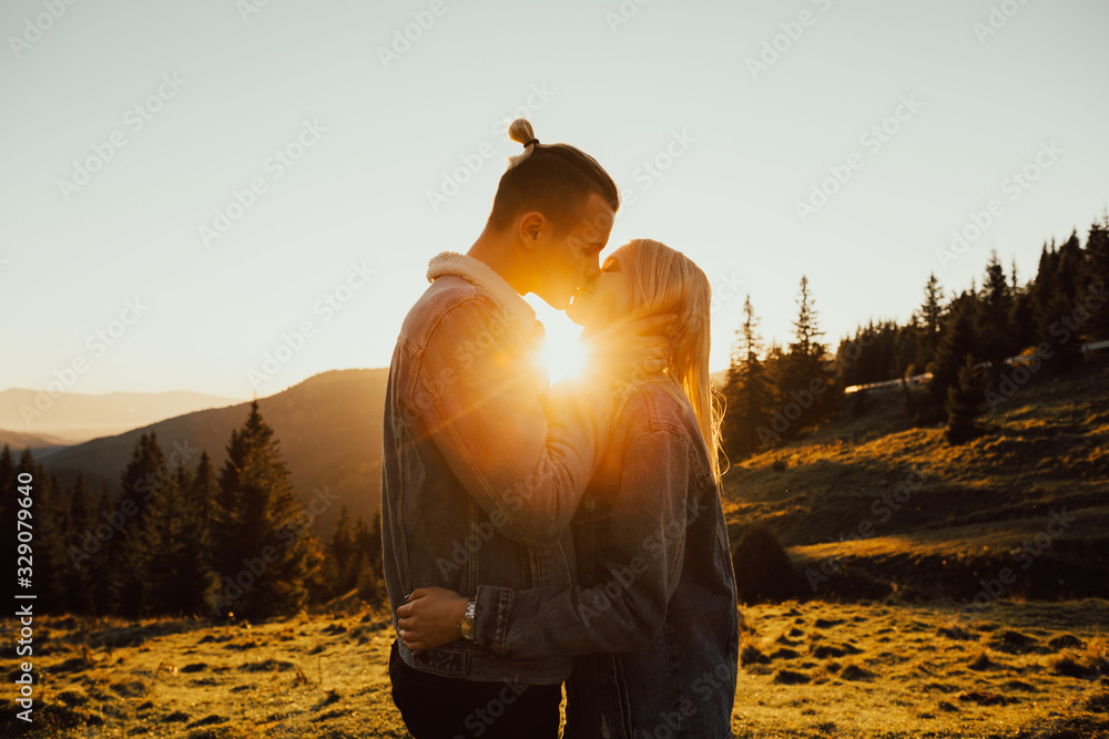 Romantic young couple kissing passionately at sunset, mountains on ...