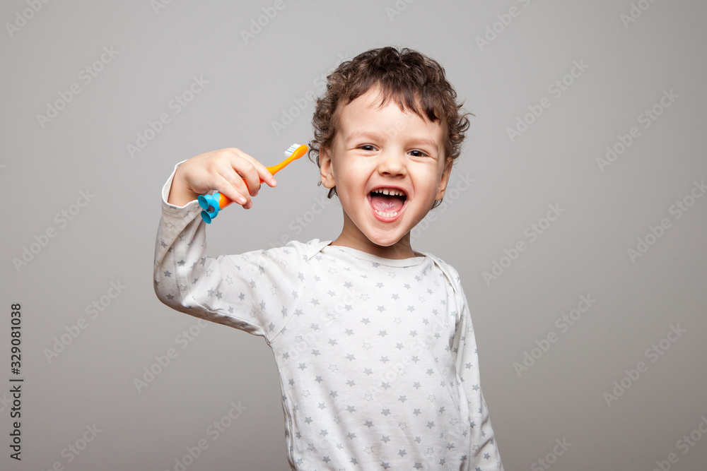 happy child, boy, with a toothbrush in his hands, laughs and rejoices ...