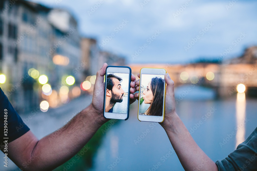 Foto de Young loving couple kissing virtually with the smart phone in ...