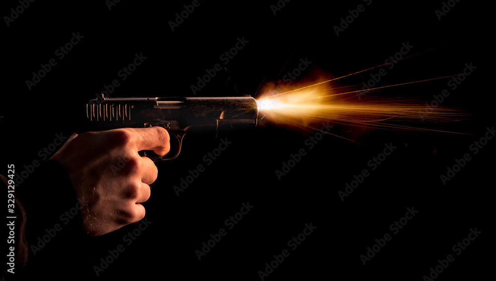 Foto de The hand presses the trigger of the gun and the flame from the ...