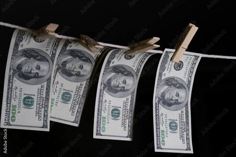 One-hundred dollar bills are hung with clothespins on a string on a ...