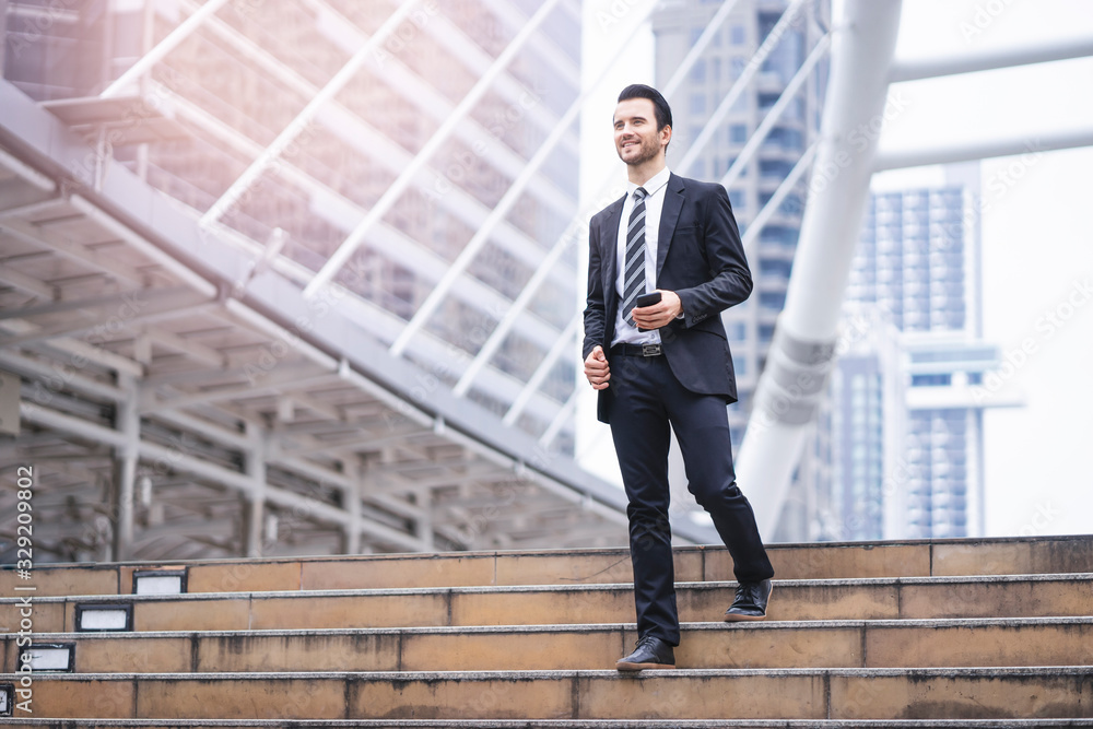 Caucasian handsome businessman confidently walking down the stairways ...