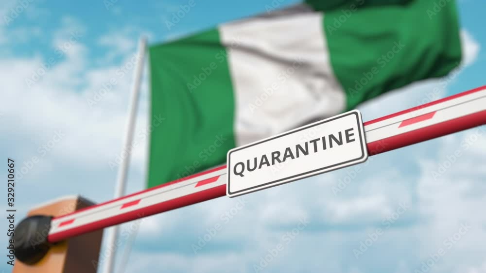 Closing boom barrier with QUARANTINE sign against the Nigerian flag ...