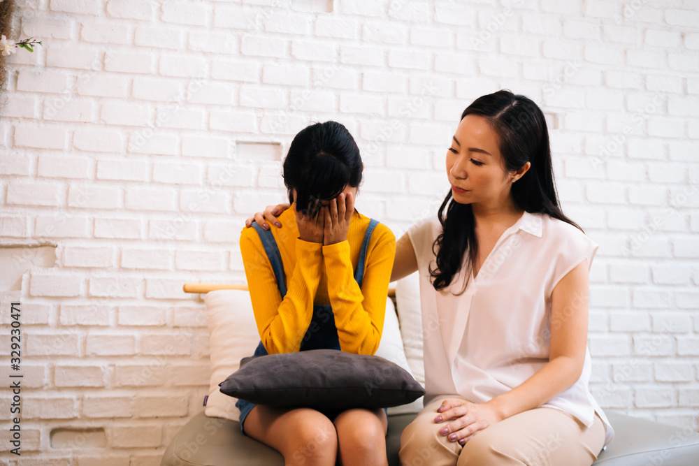 Asian mother comforting crying teenage daughter in miserable, stressed ...