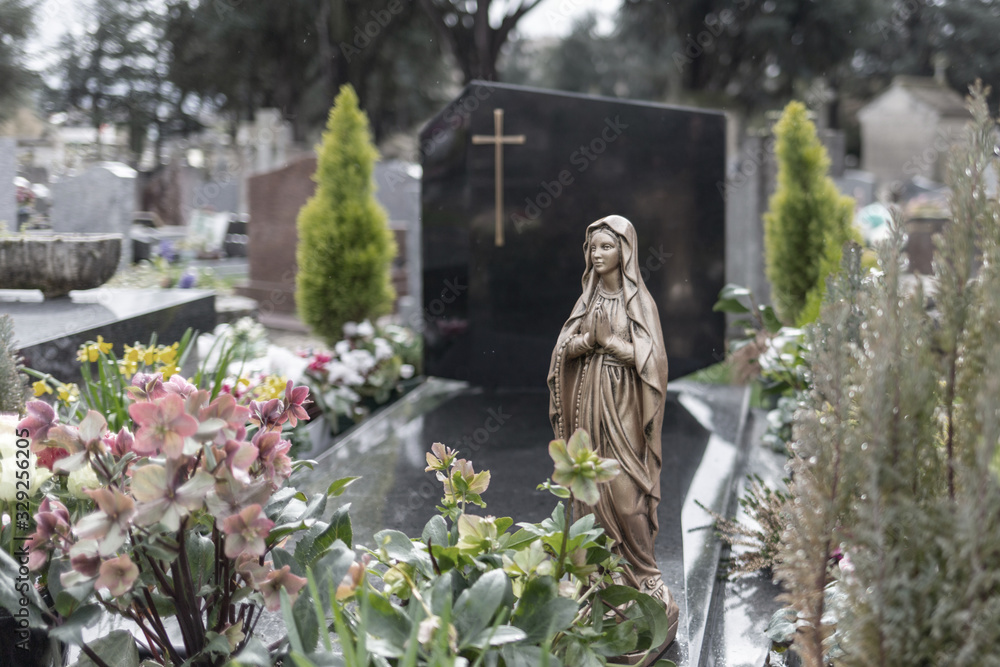 Virgin Mary at cemetery, graveyard background, tombstone desaturated ...