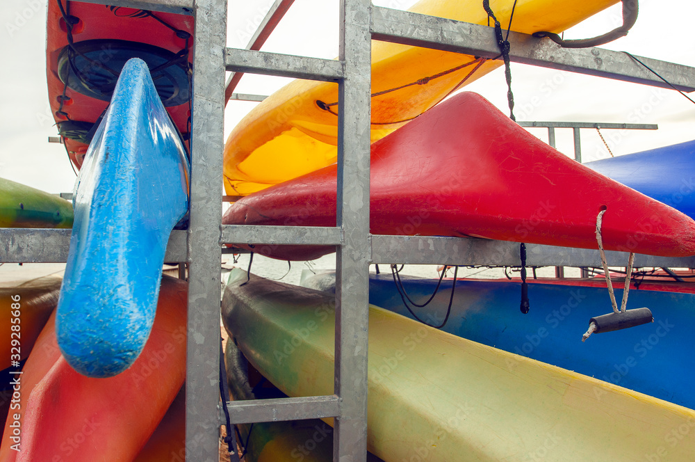 Multi-colored kayaks on the seashore. Multi-colored canoes parked in a ...