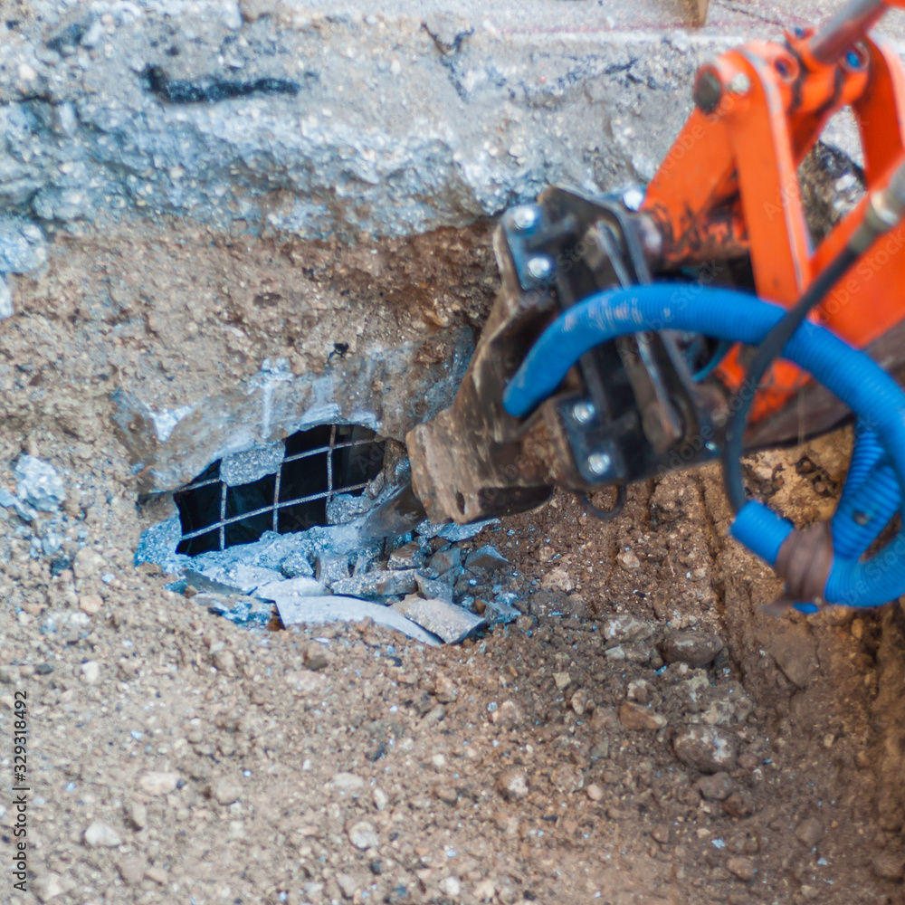 mini excavator equipped with pneumatic hammer it breaches a reinforced ...
