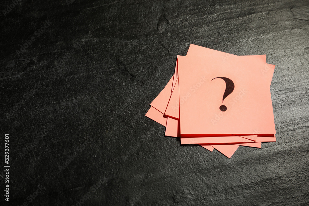 Pink paper cards with question mark on black stone table, top view ...