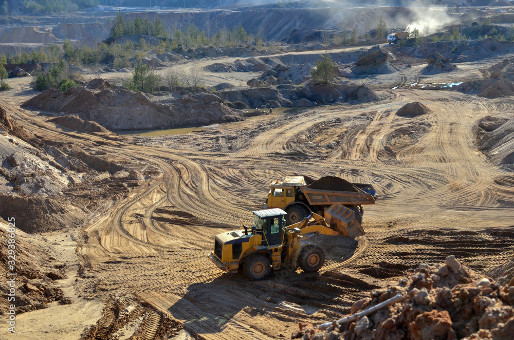 Foto de Wheel loader loads sand into heavy mining dump truck at the ...