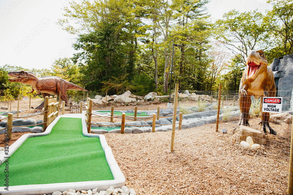 Dinosaur sculptures in miniature golf course against forest Stock Photo ...
