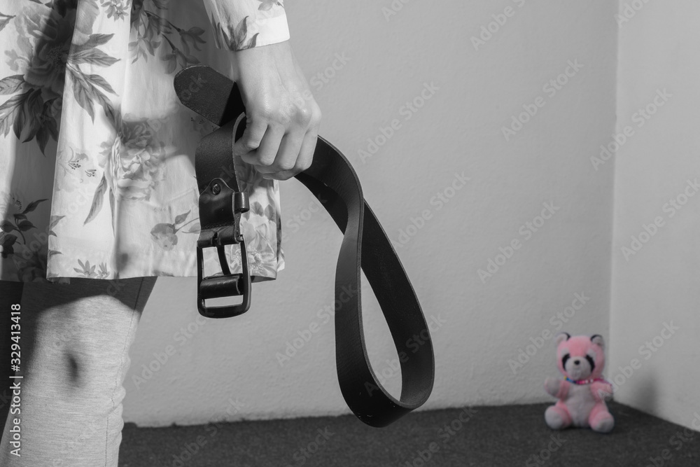 Child abuse concept. A girl in a colored dress sits in a corner, covers ...