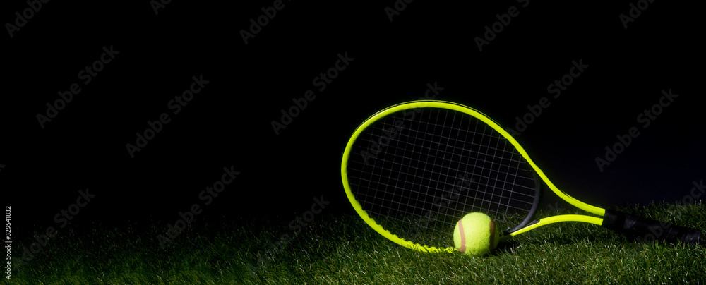 Green tennis racket with tennis balls in green color on grass with ...