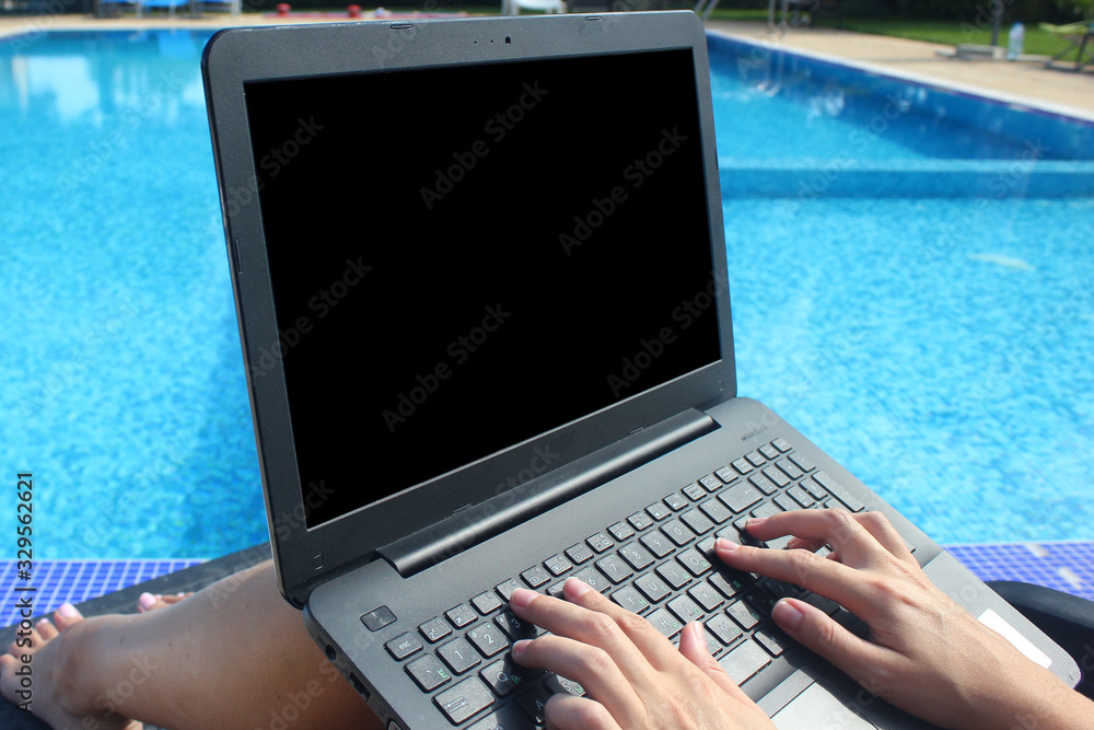 Screen mockup of laptop used by young woman laying near swimming pool ...