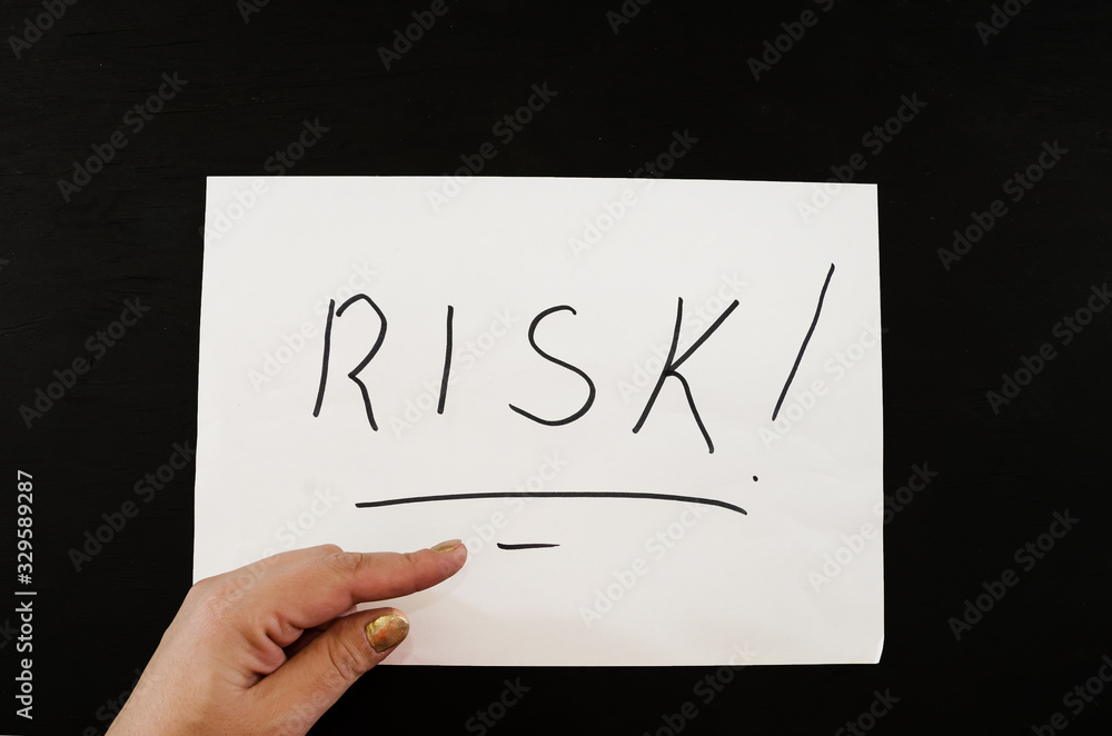 RISK inscription on white. Hand points to the word "risk" written on a ...