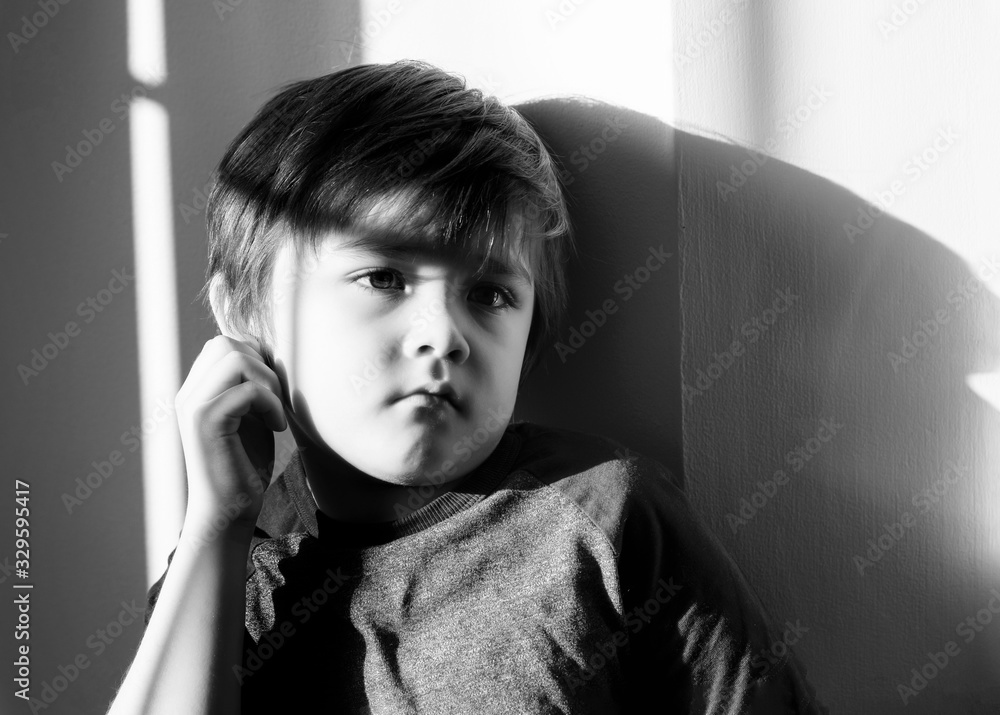 High key light portrait of Sad boy standing next to wall, Black and ...