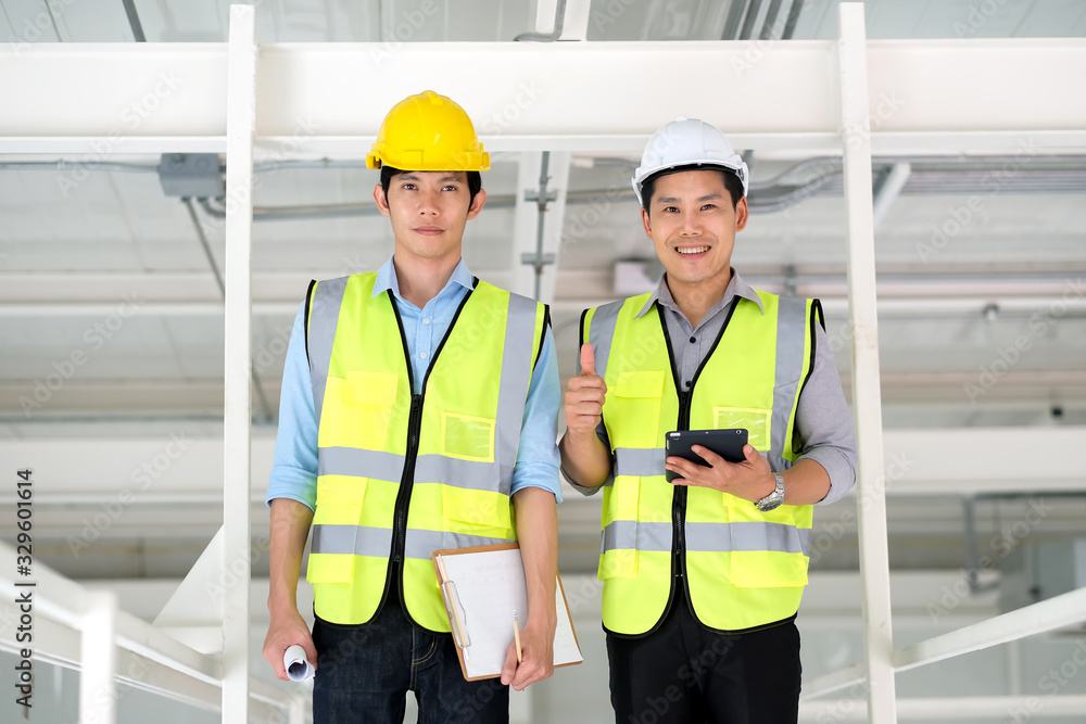 Two engineers man standing in the site. Engineer holding tablet and ...
