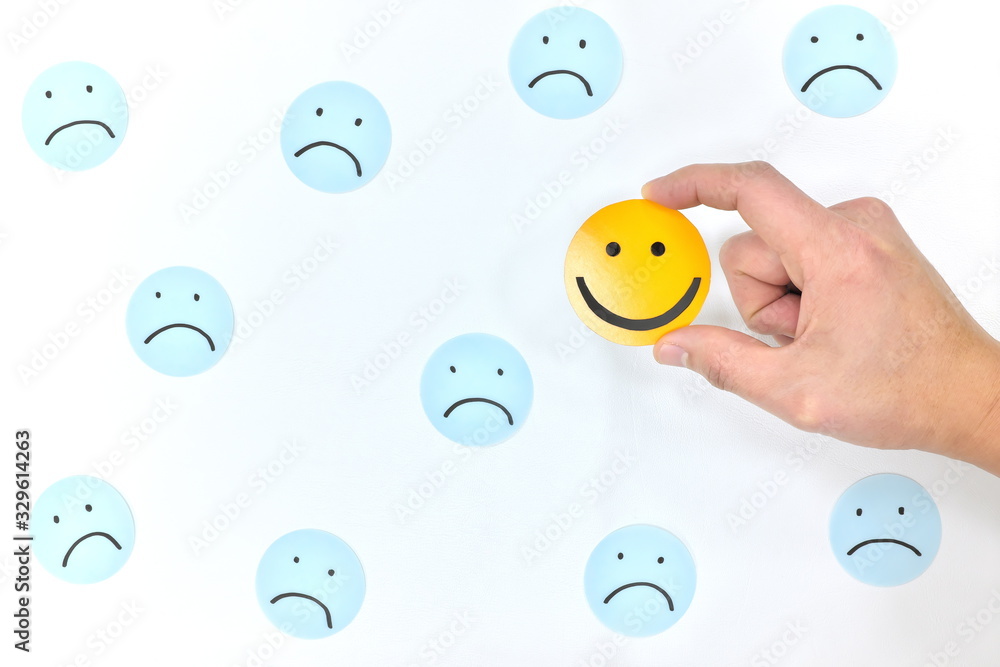 A smiling face icon among a set of sad face emoticons. Stay positive ...