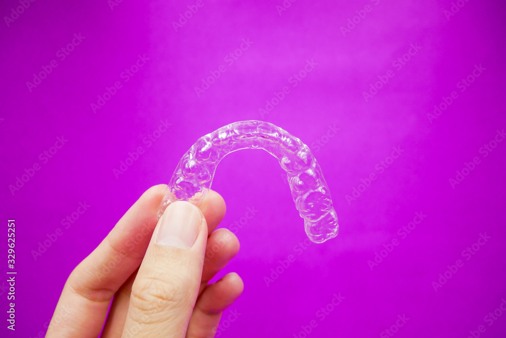hand holding clear plastic retainer teeth that isolated on purple ...