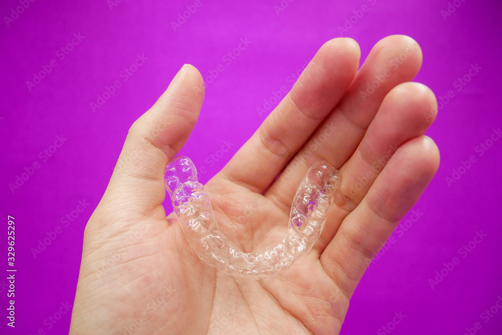 hand holding clear plastic retainer teeth that isolated on purple ...