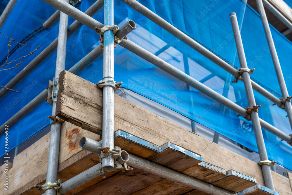 scaffolding poles and screen on a building on a construction site or ...