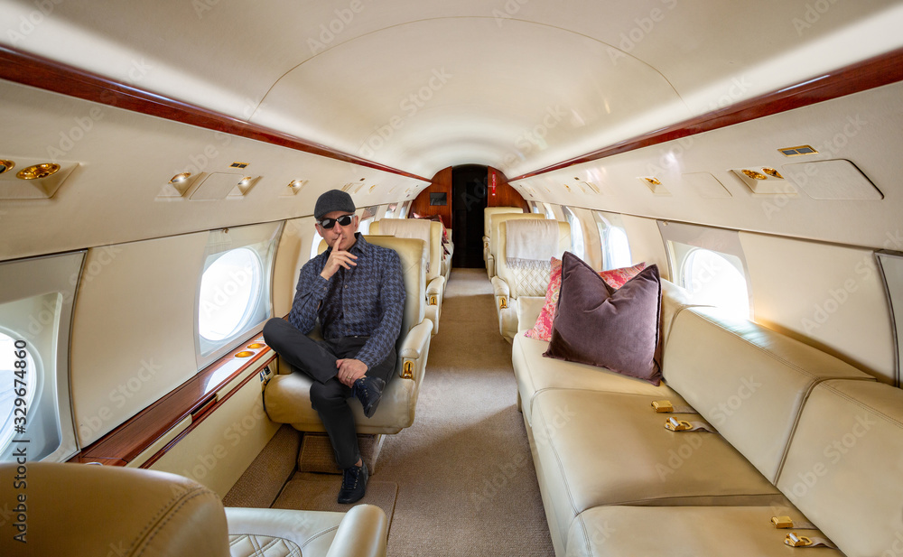 Handsome man sitting inside a private jet alone. Stock Photo | Adobe Stock