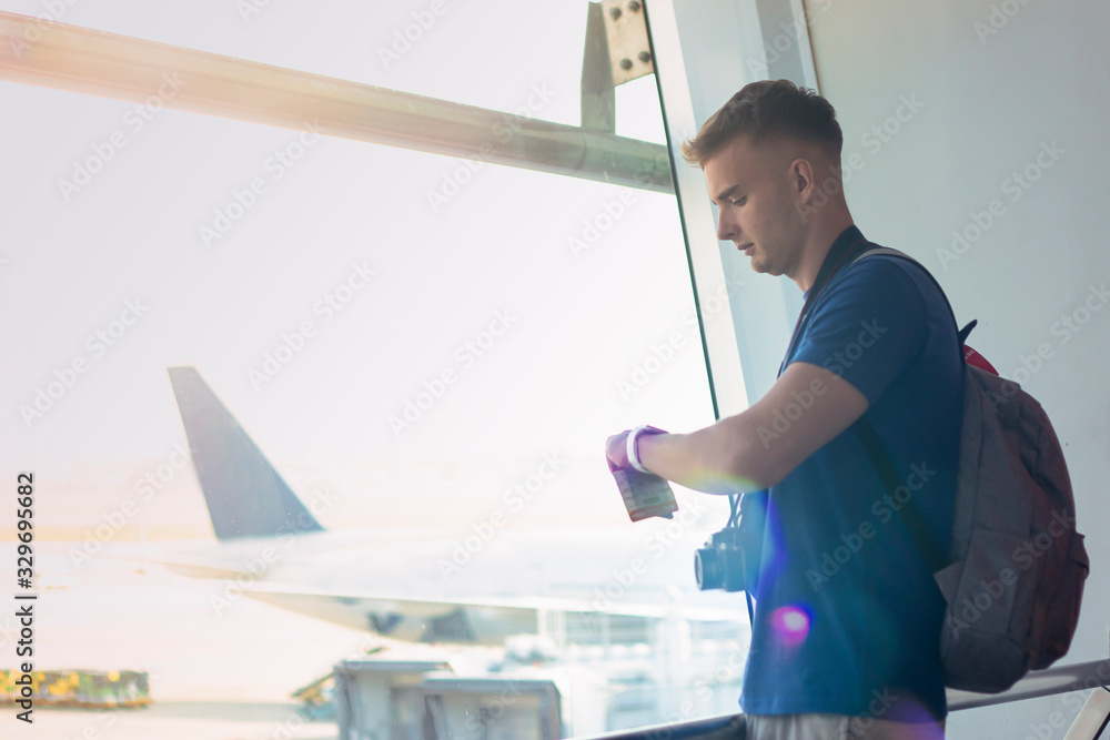 A man guy is standing in the airport, in the waiting room. View through ...