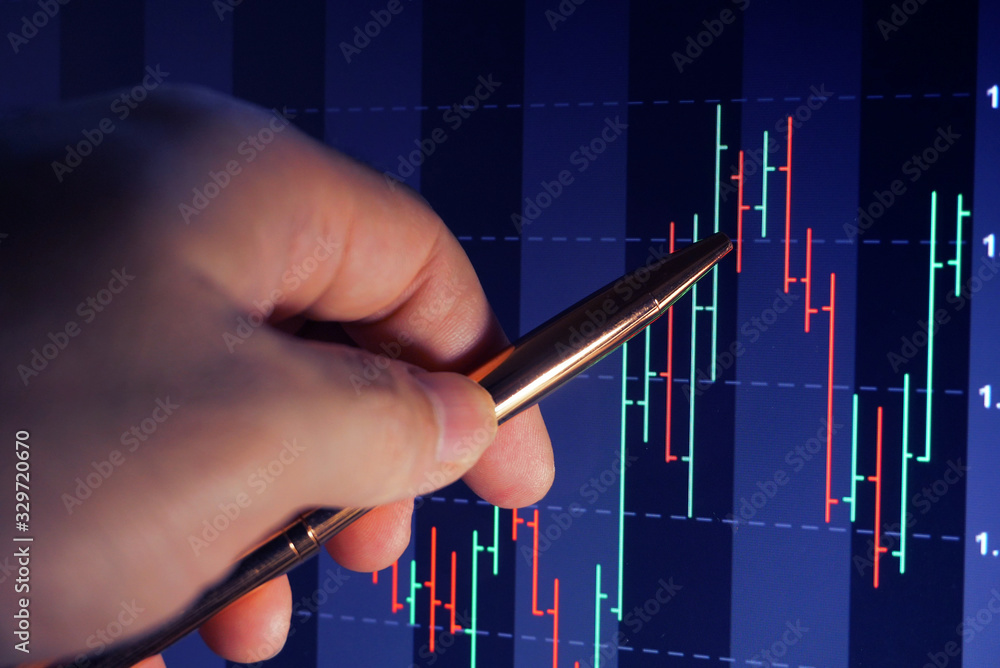 Trader 's hand point pen on chart trading screen before have circuit ...