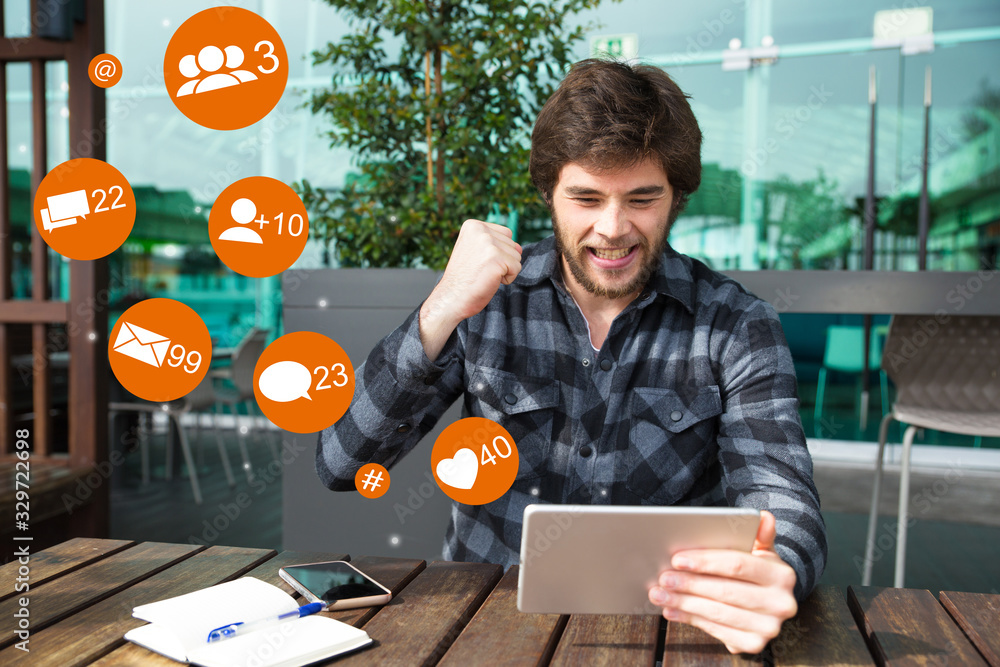 Happy man using tablet and celebrating success in outdoor cafe ...