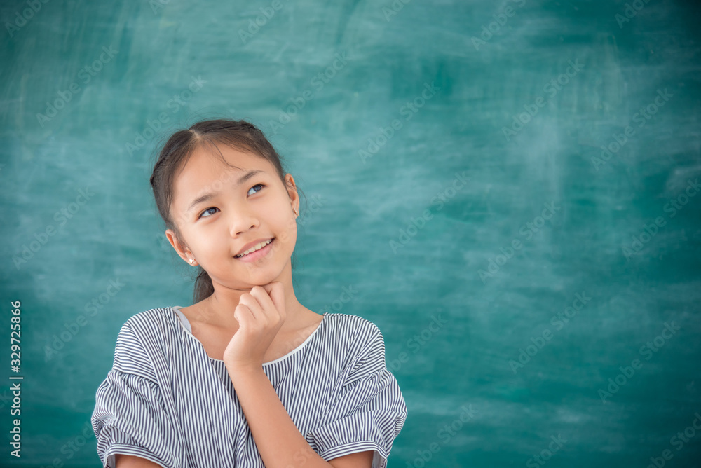 Young asian female student thinking and smiles in front of green ...