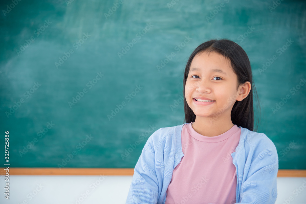 Young asian female student standing and smiles in front of green ...