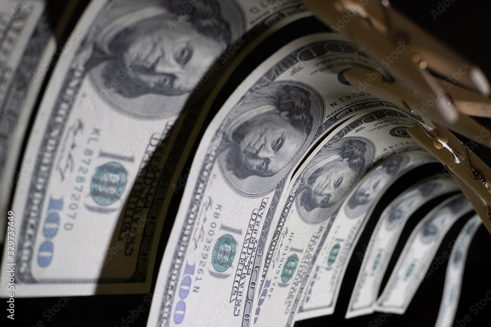 One-hundred dollar bills are hung with clothespins on a string on a ...