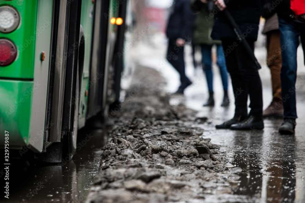 Foto de people are standing at a bus stop, getting on a bus stepping ...