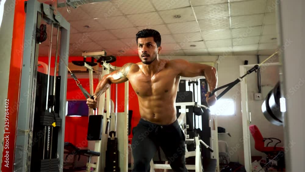 Muscular bodybuilder at cable crossovers fitness men pumping up muscles ...