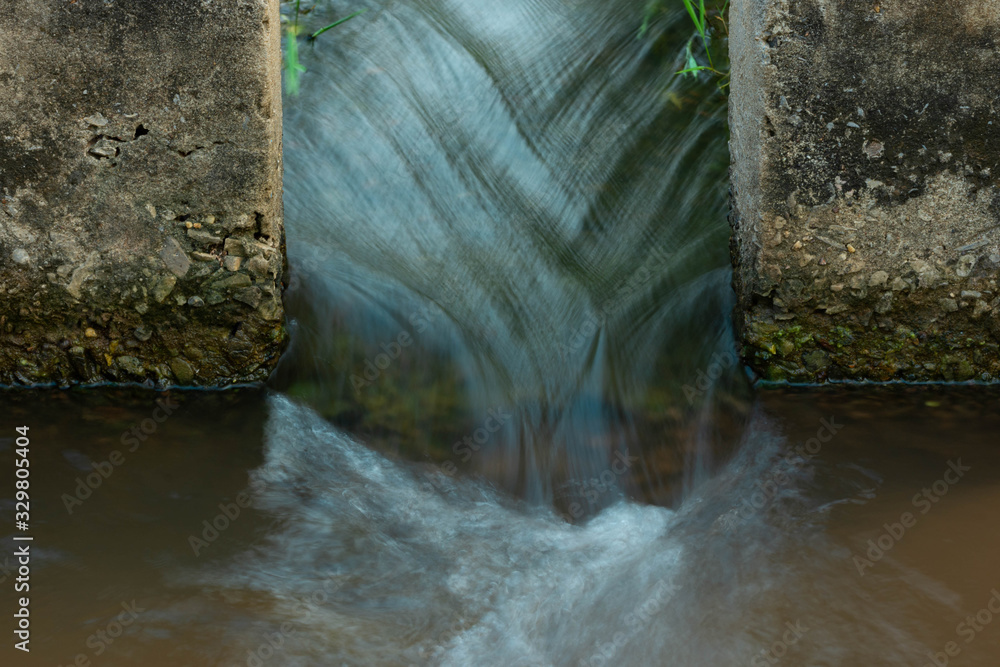 Water flows through the floodgate in the irrigation canal quickly.Water ...