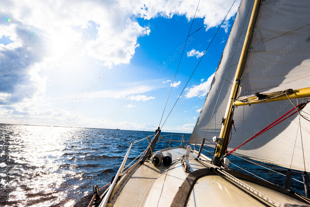 Sloop rigged yacht sailing on a clear day. A view from the deck to the ...