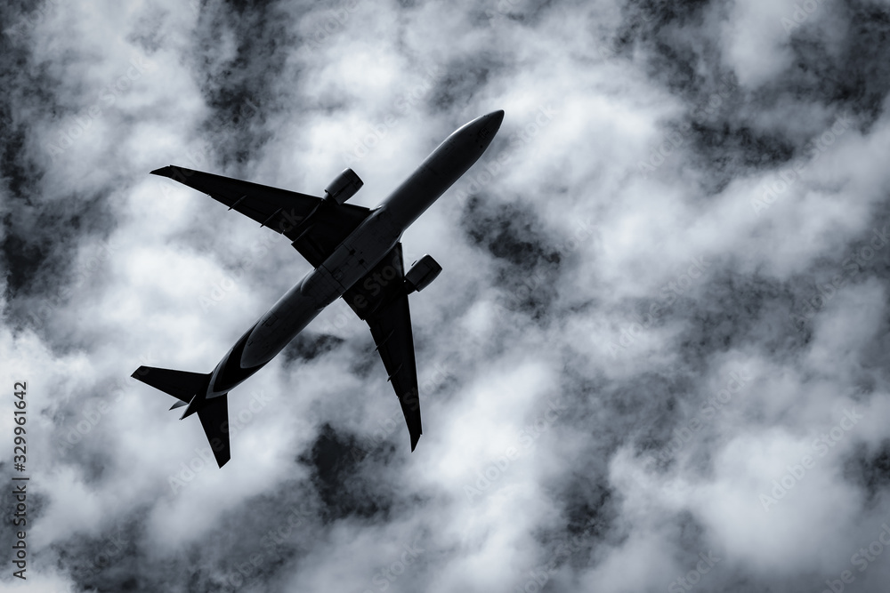 Commercial airline flying on dark sky and white fluffy clouds. Under ...