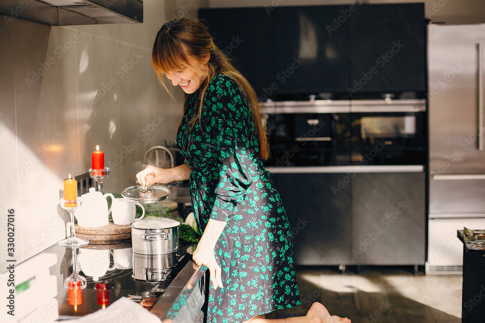 Beautiful woman in a green dress. Lady working in a kitchen Stock Photo ...