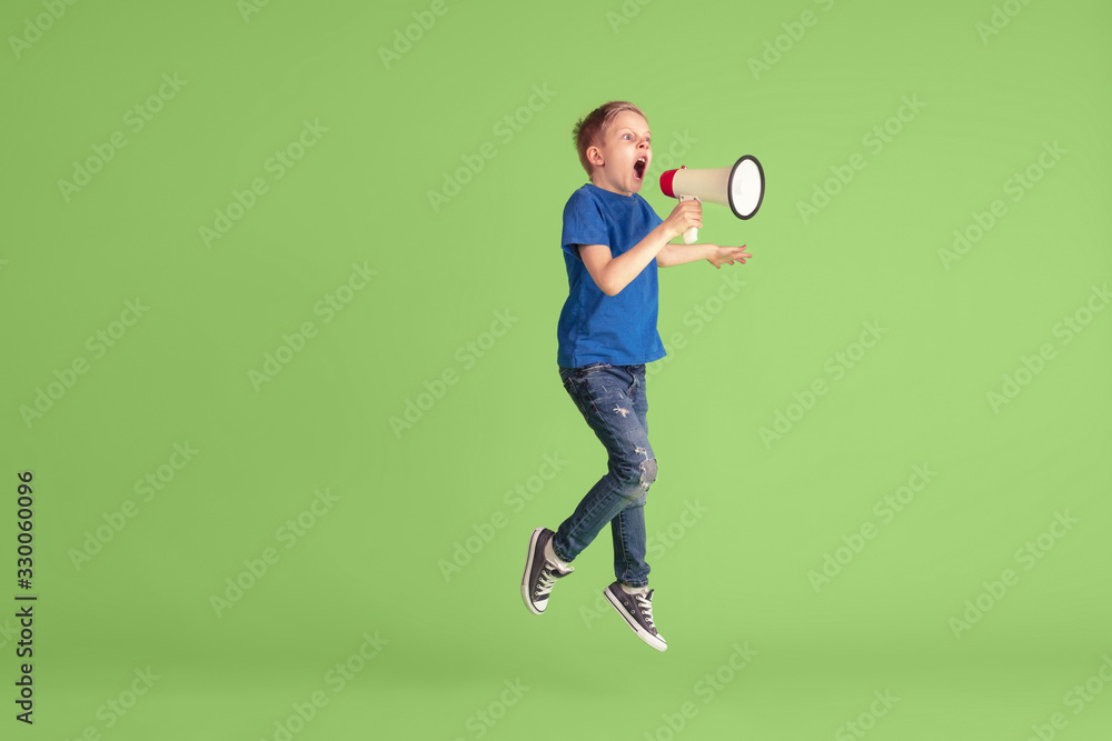 Shouting, calling. Happy boy playing and having fun on green studio ...