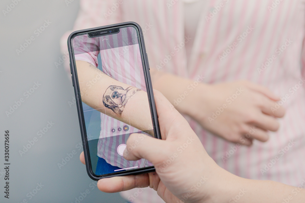 Tattoo artist taking a photo to finished tattoo in a womans arm with ...