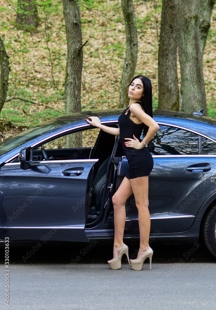 Model that stands out. Fashion model pose at automobile. Sensual woman ...