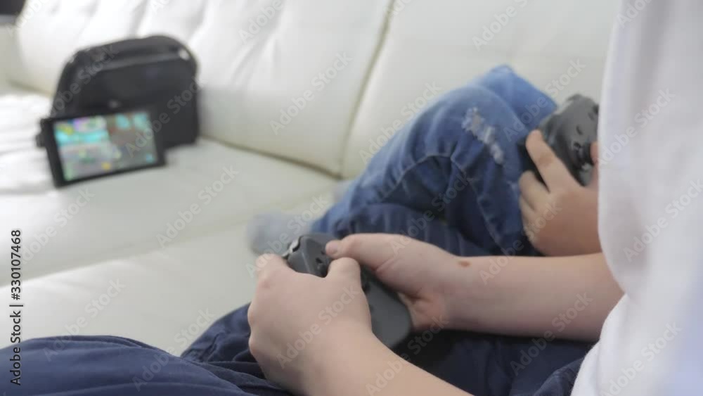 children play console in gamepads teamwork. kids a boy and a girl are ...